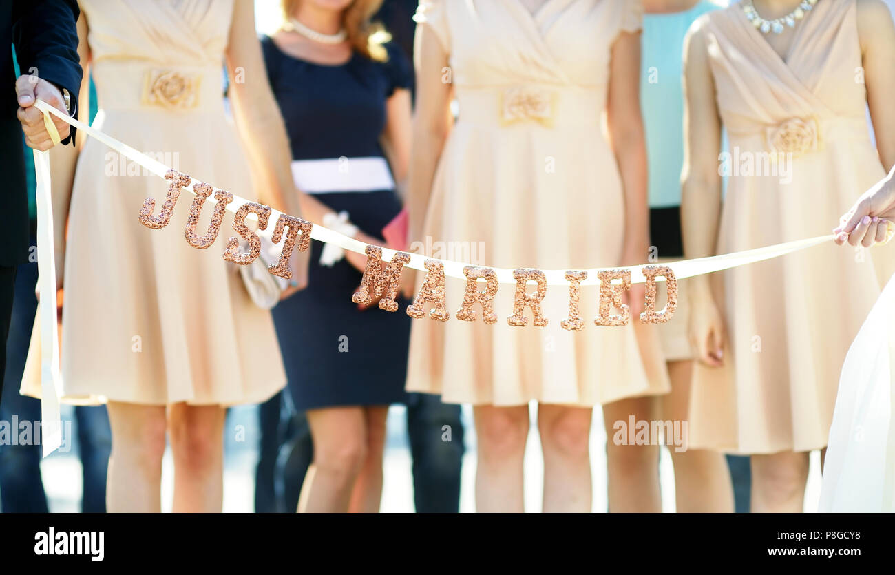 Bride and groom holding glittery "Just married" sign Stock Photo - Alamy