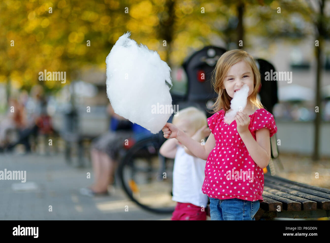 Adorable little girl eating candy-floss outdoors at summer Stock Photo ...