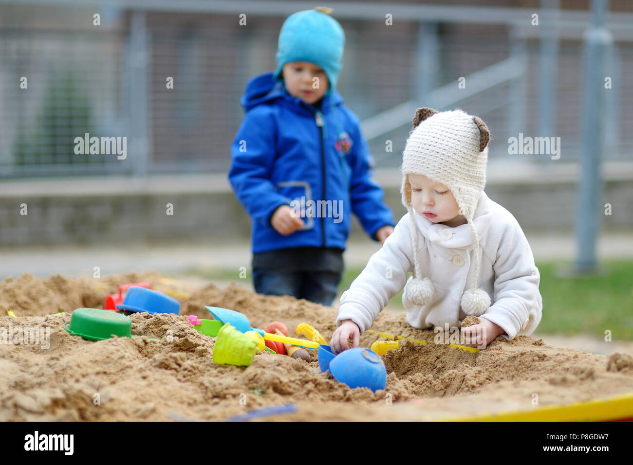 Two kids playing in a sandbox on autumn day Stock Photo - Alamy
