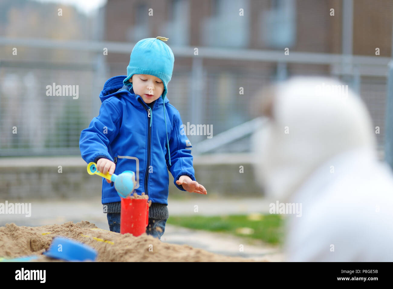 Two kids playing in a sandbox on autumn day Stock Photo - Alamy