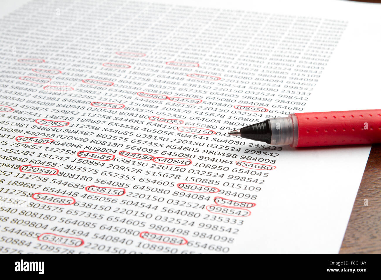 Red pen sitting on a piece of paper with numbers circled. Paper looks ...