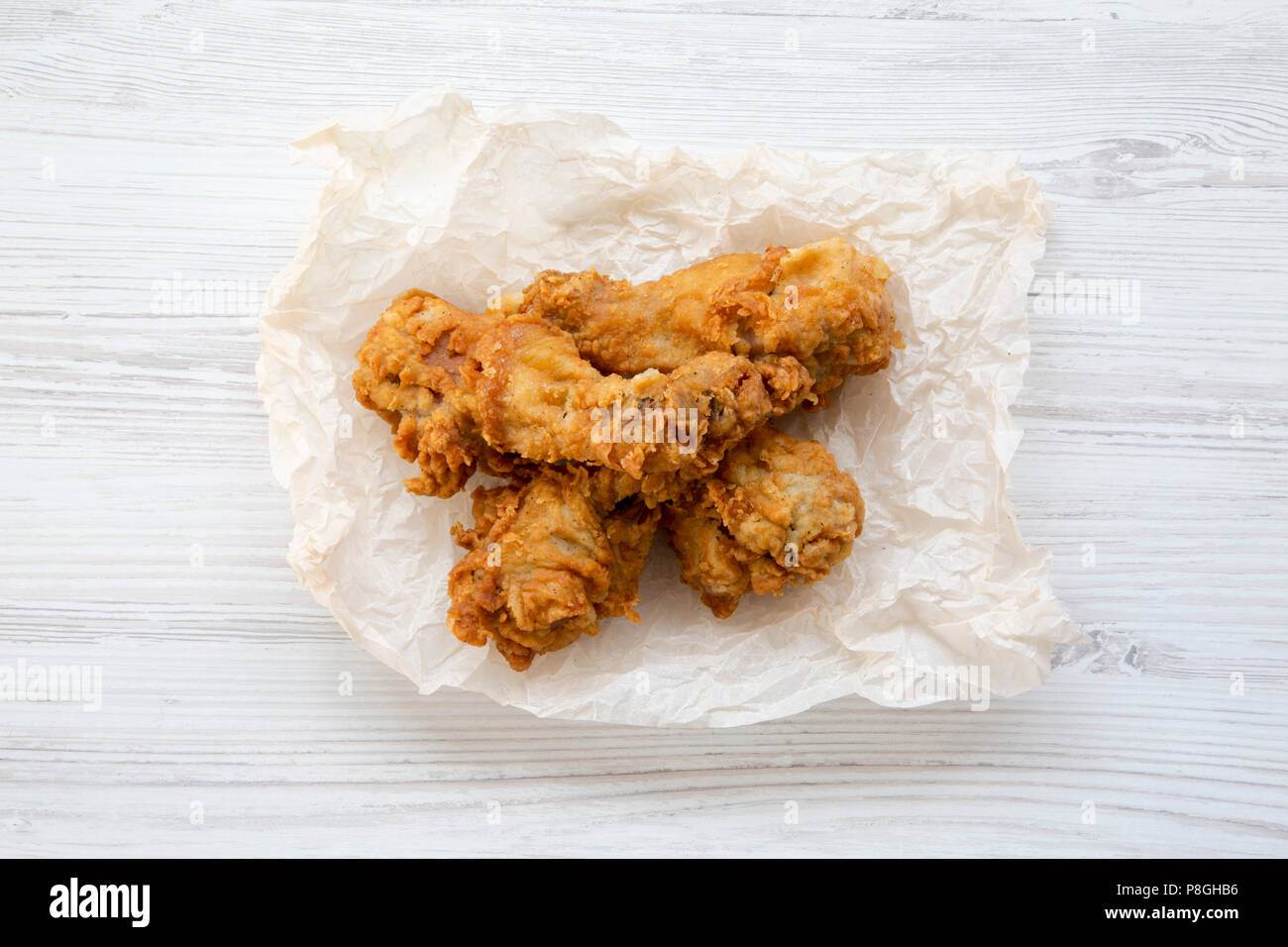 Fried chicken legs on white wooden surface, view from above. Overhead ...