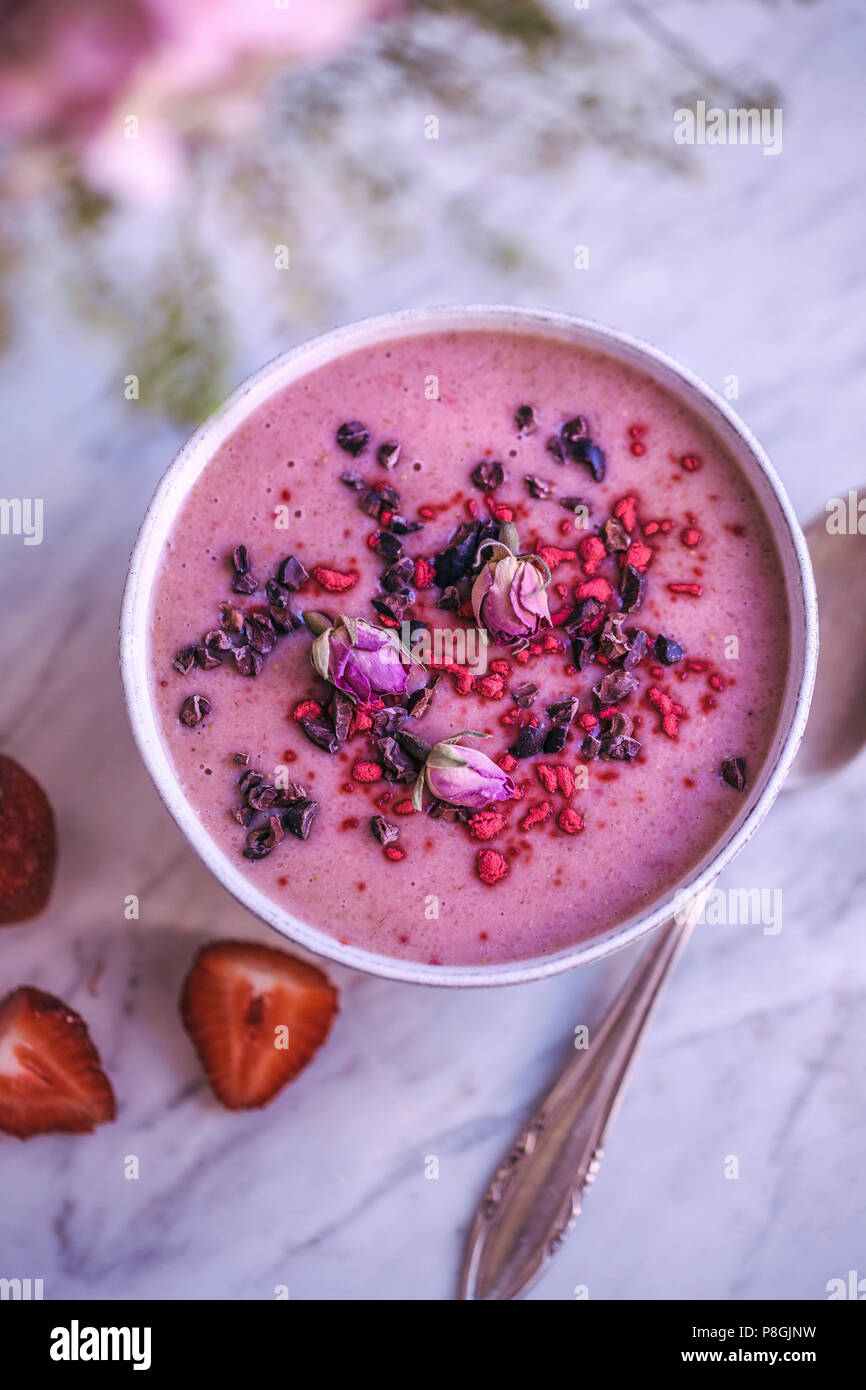 Strawberry smoothie bowl topped with cacao nibs, raspberry powder and ...