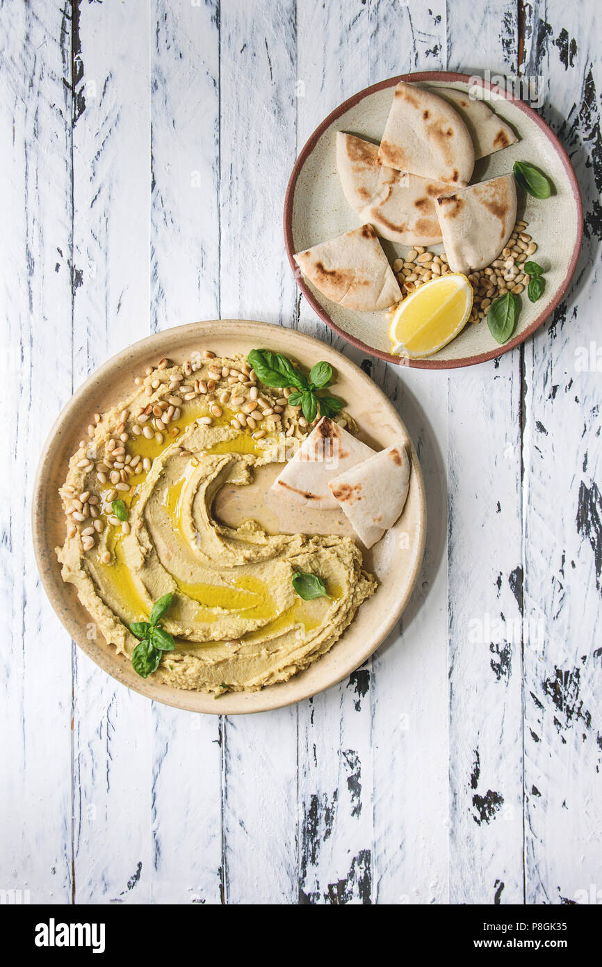 Homemade traditional spread hummus with pine nuts, olive oil, basil ...