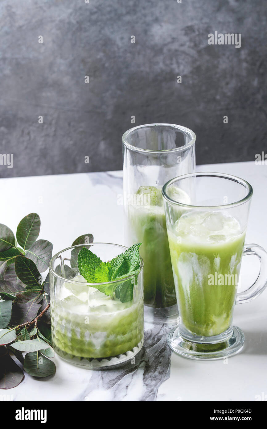 Matcha green tea iced latte or cocktail in three different glasses with ...