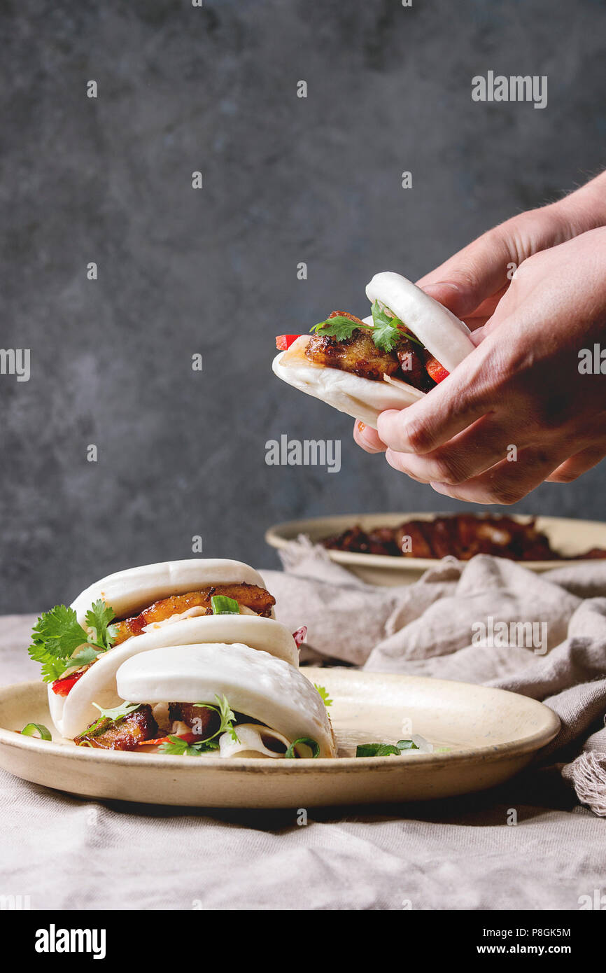 Man's hands hold asian sandwich steamed gua bao buns with pork belly ...