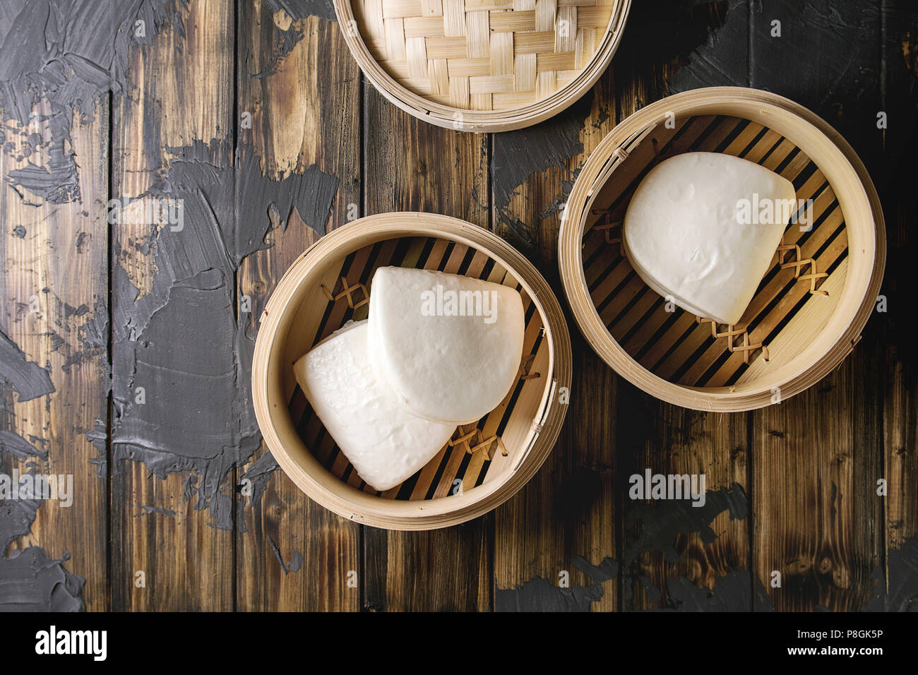 Empty gua bao steamed buns in opened bamboo steamer over dark wooden ...