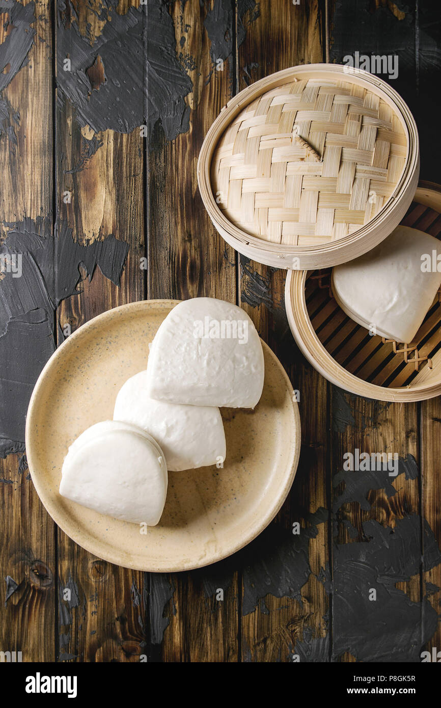 Empty gua bao steamed buns in ceramic plate and opened bamboo steamer ...