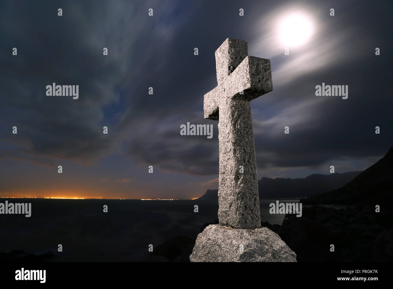 Scary stone cross seen at night with the moon and clouds in the ...