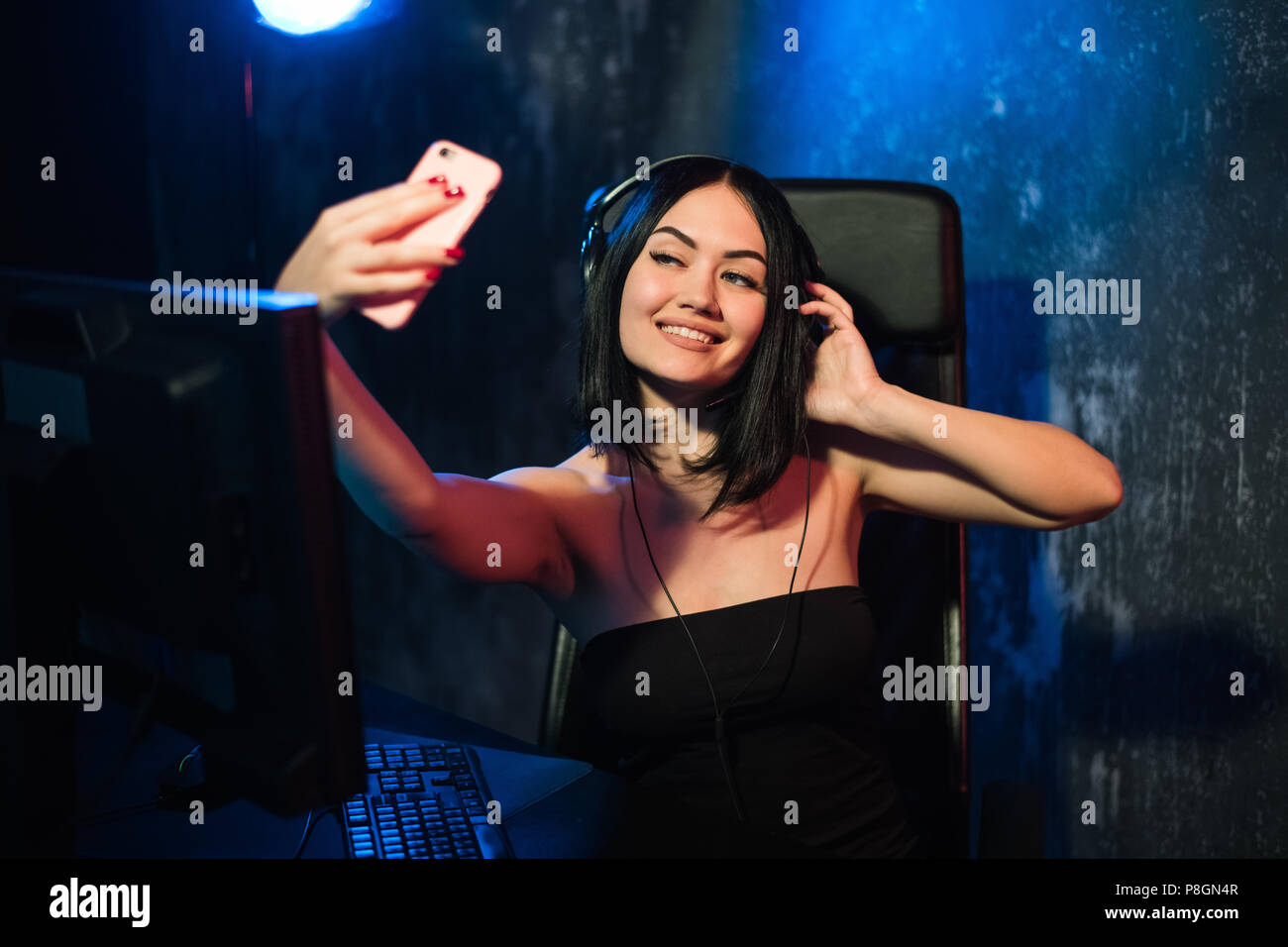 Cheerful gamer streamer girl wearing headset and sitting near her pc ...