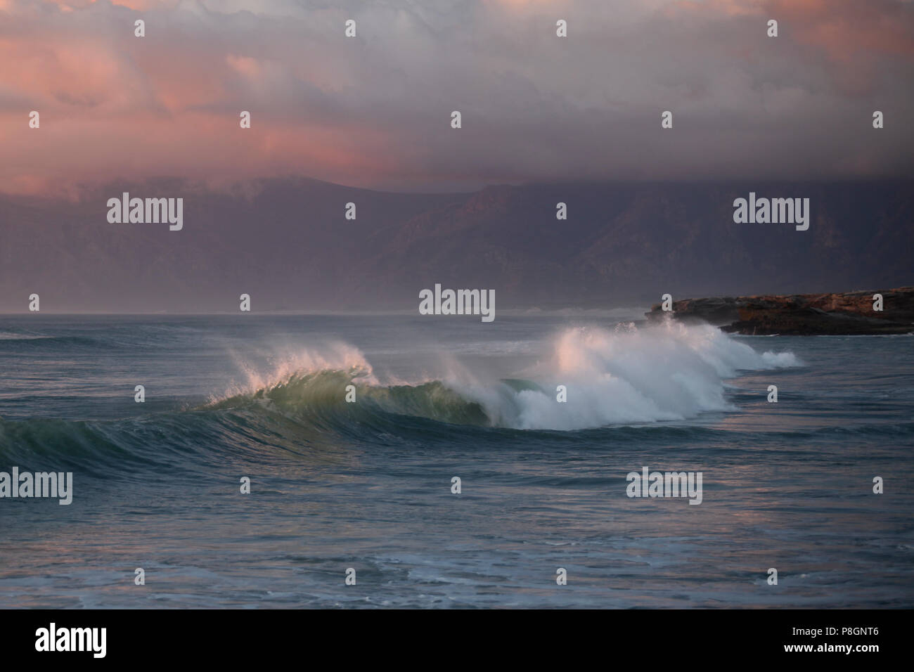 Wave breaking with colorful sunset in background Stock Photo - Alamy