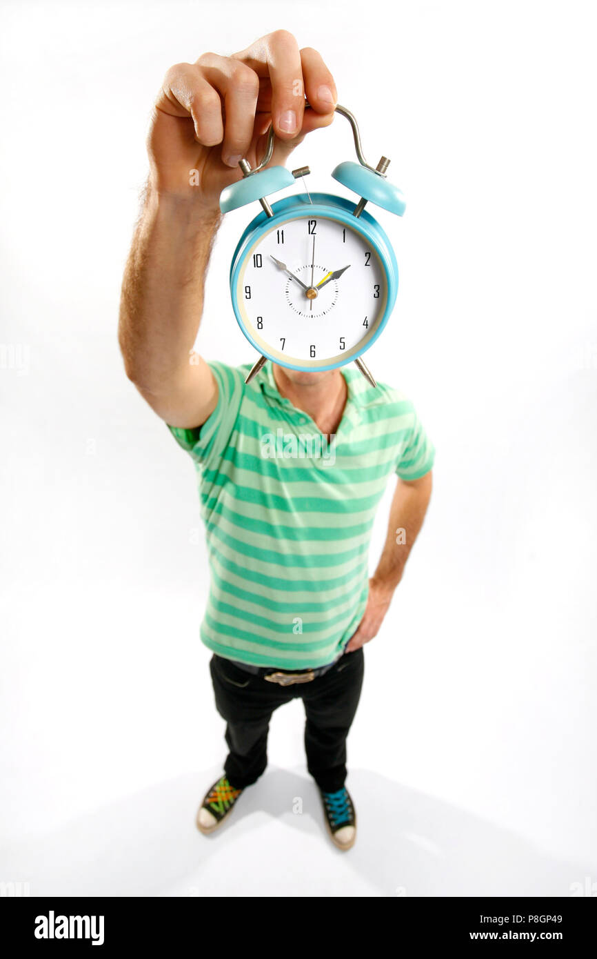Man holding up a clock in front of his face showing the time Stock ...