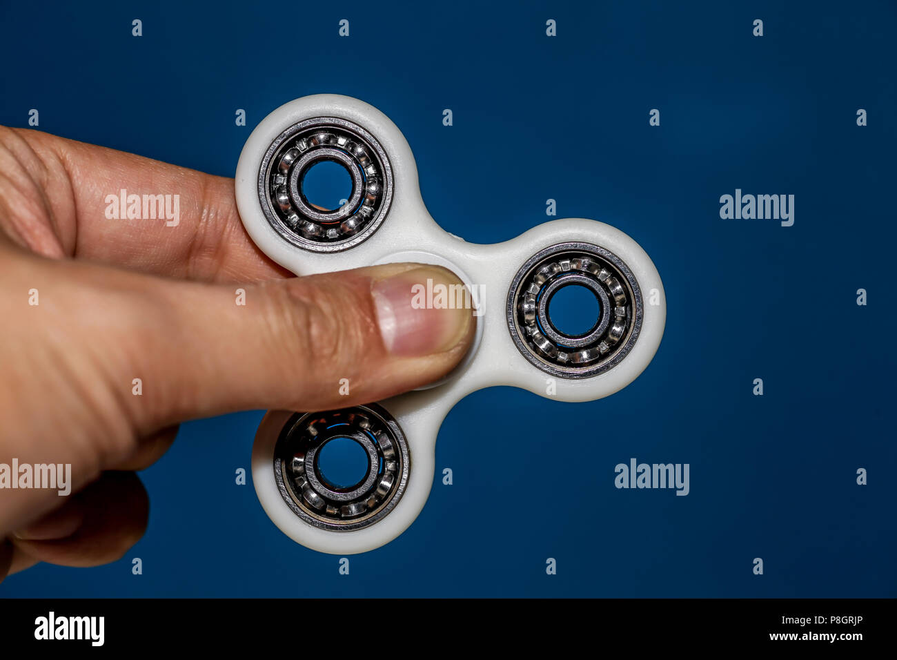 Hand holding a stationary fidget spinner with blue background Stock ...