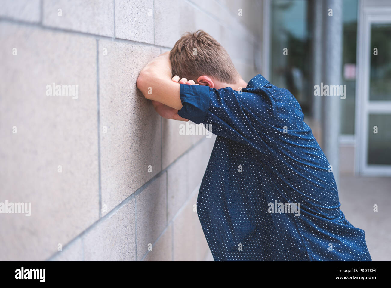 Teen crying into folded arms against a brick wall Stock Photo - Alamy