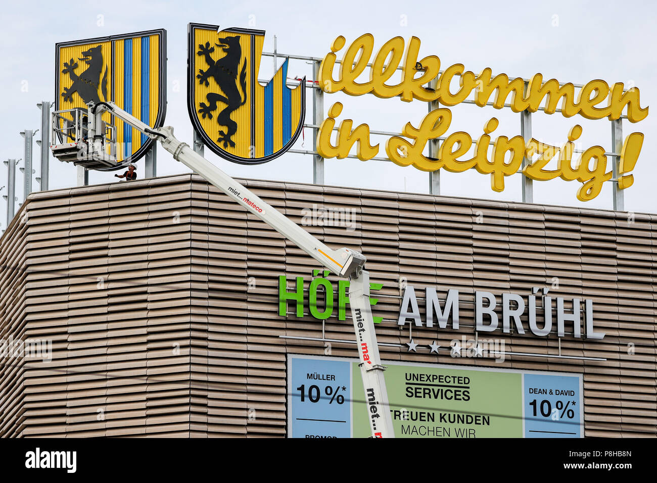 Leipzig, Germany. 11th July, 2018. Technicians attach a neon sign with ...