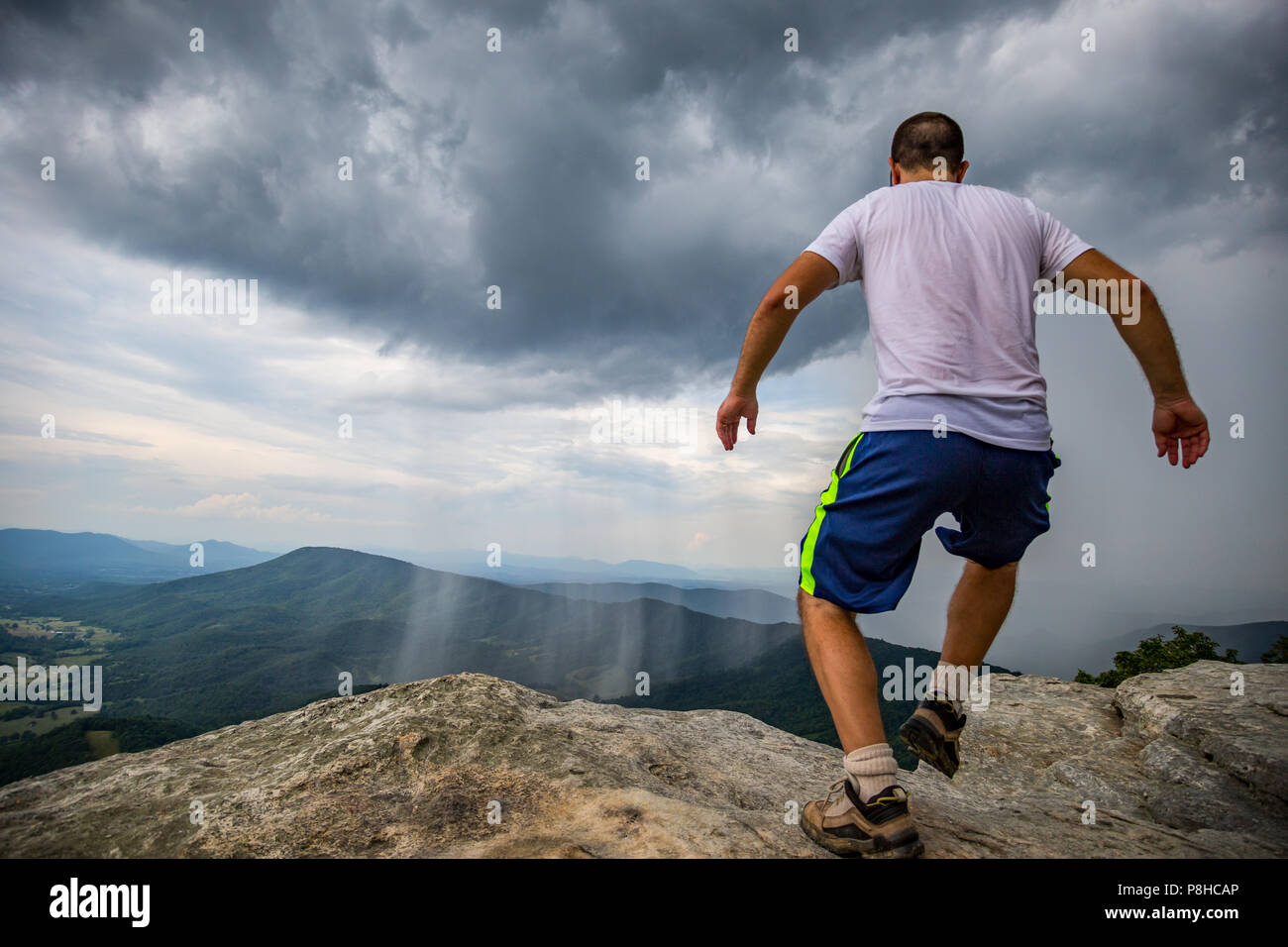 Man Running Towards the edge of McAfee Knob edge above scenic stormy ...
