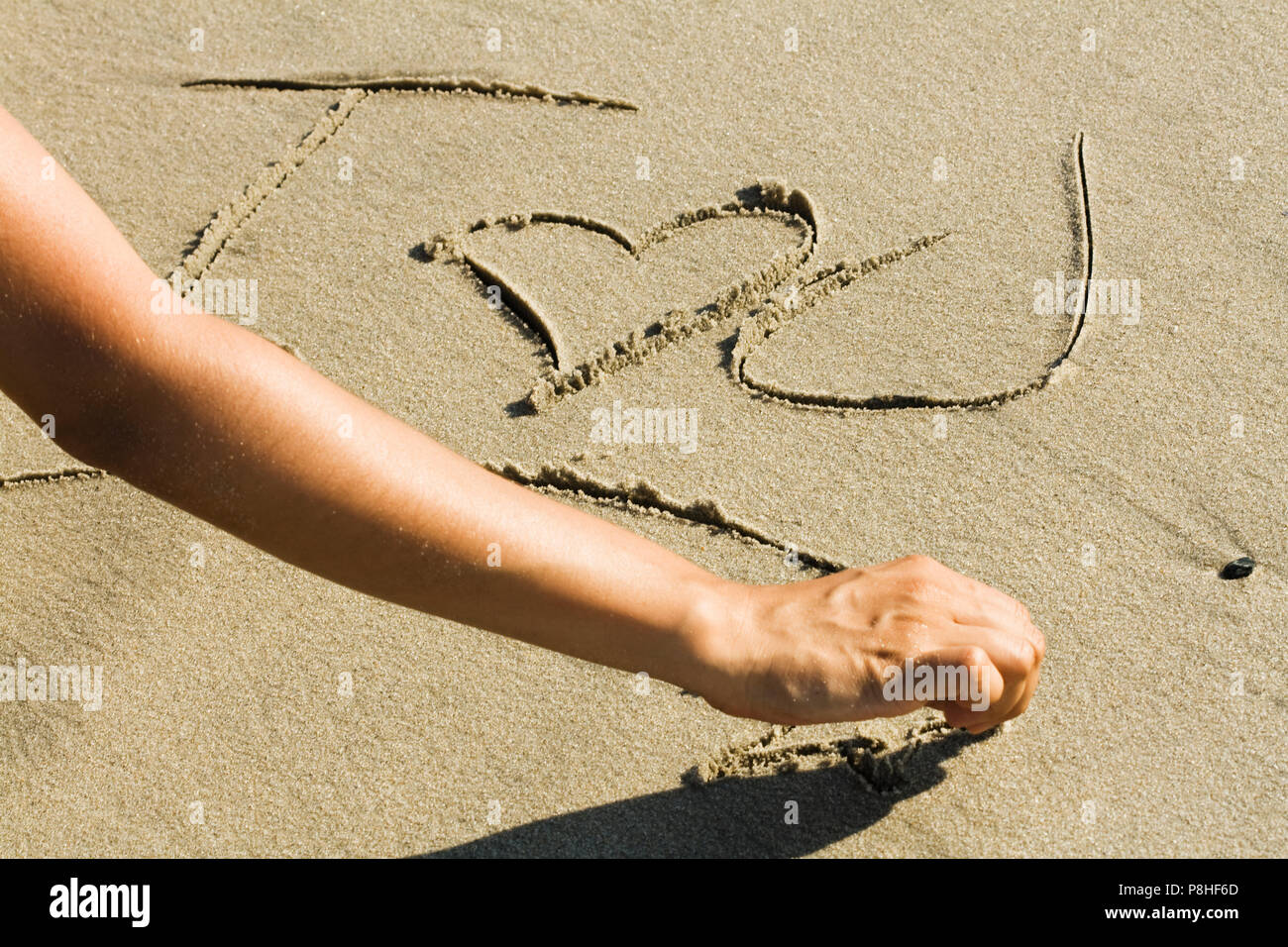 Young woman writing I love you on sand Stock Photo - Alamy