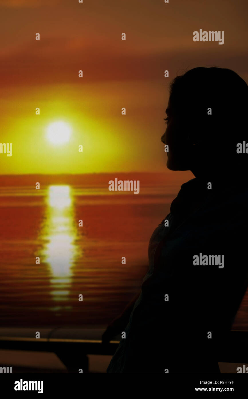 Young woman observing the sunset at the beach Stock Photo - Alamy