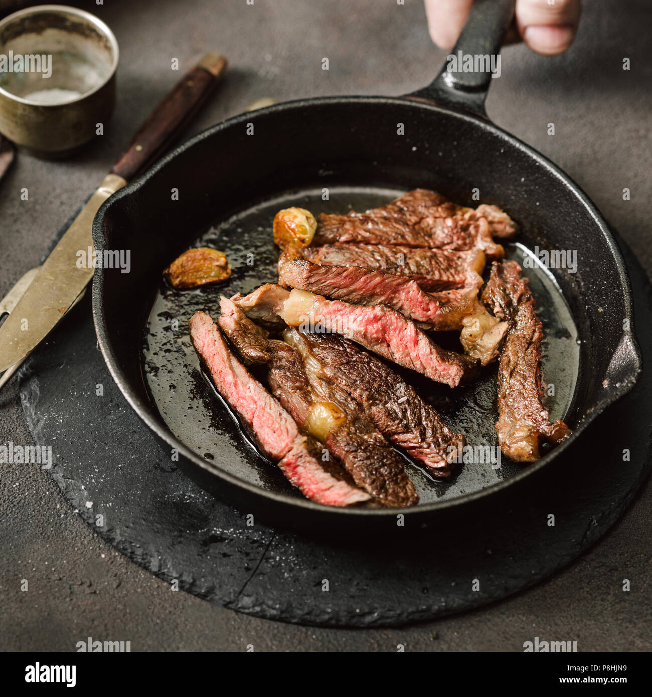 Slices juicy roast beef steak on vintage cast-iron frying pan top view ...