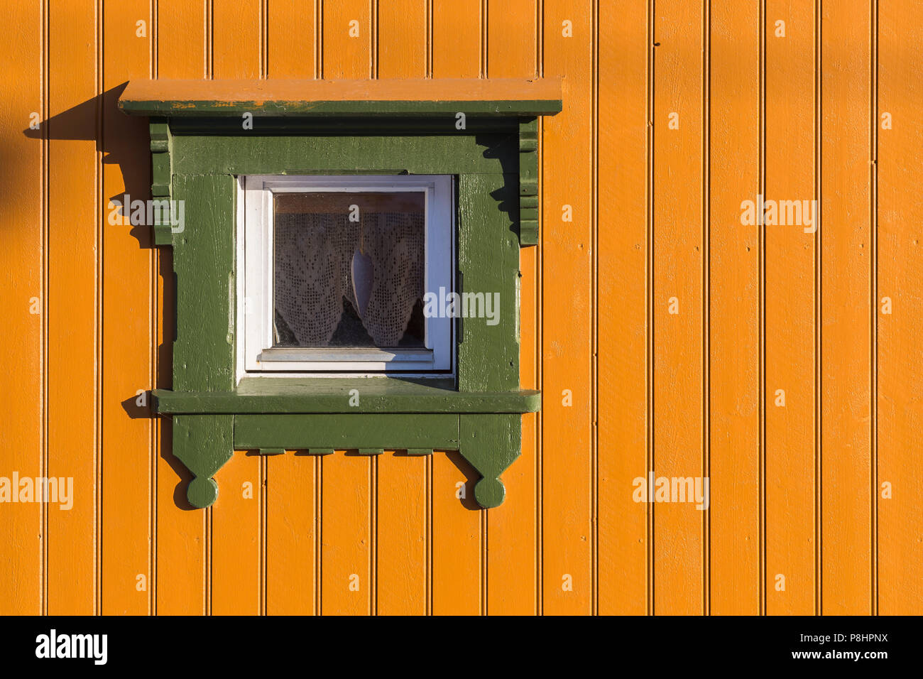 Square window in bright yellow painted timber wall with green frame ...