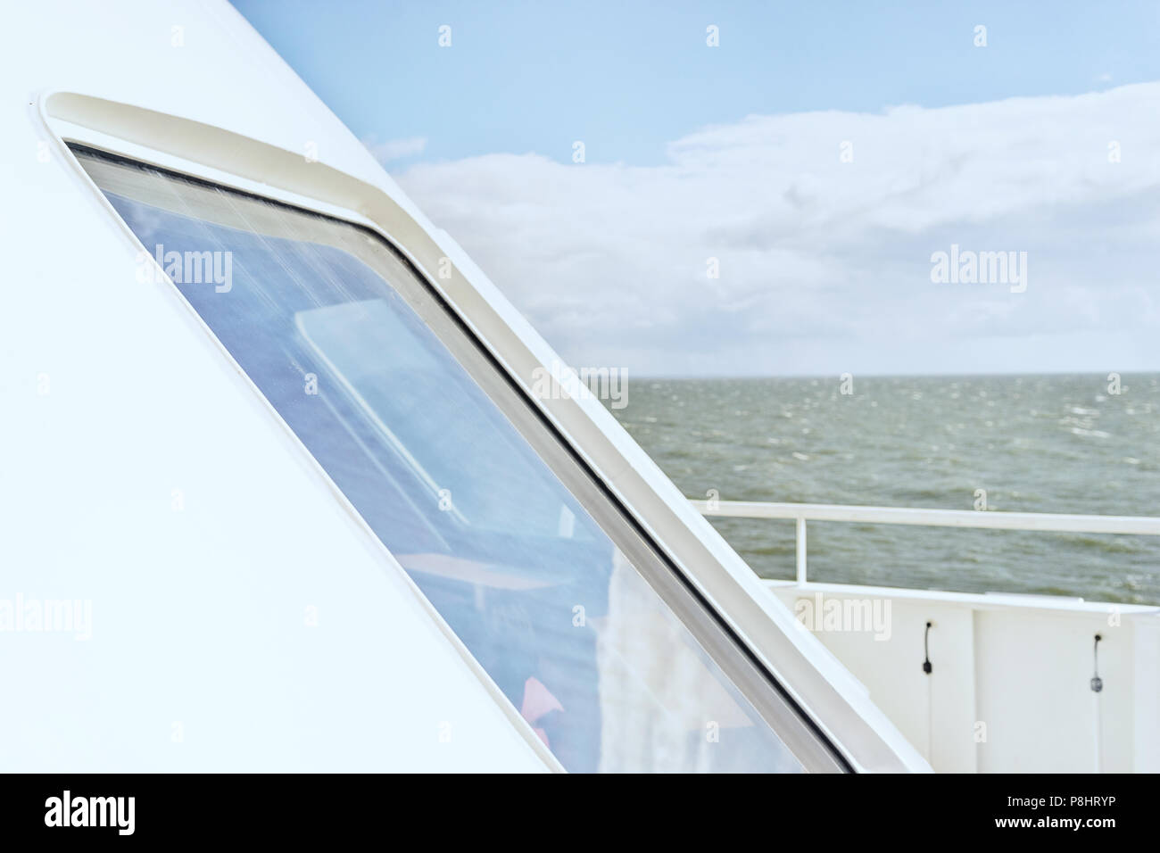 Window of a porthole on a ship on a cloud background and a railing on a ...