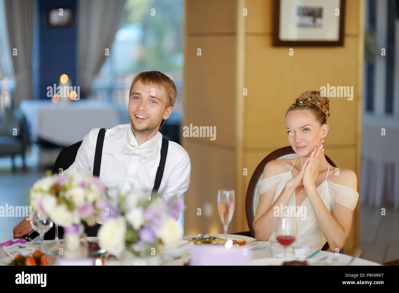 Happy bride and groom at the reception table Stock Photo - Alamy