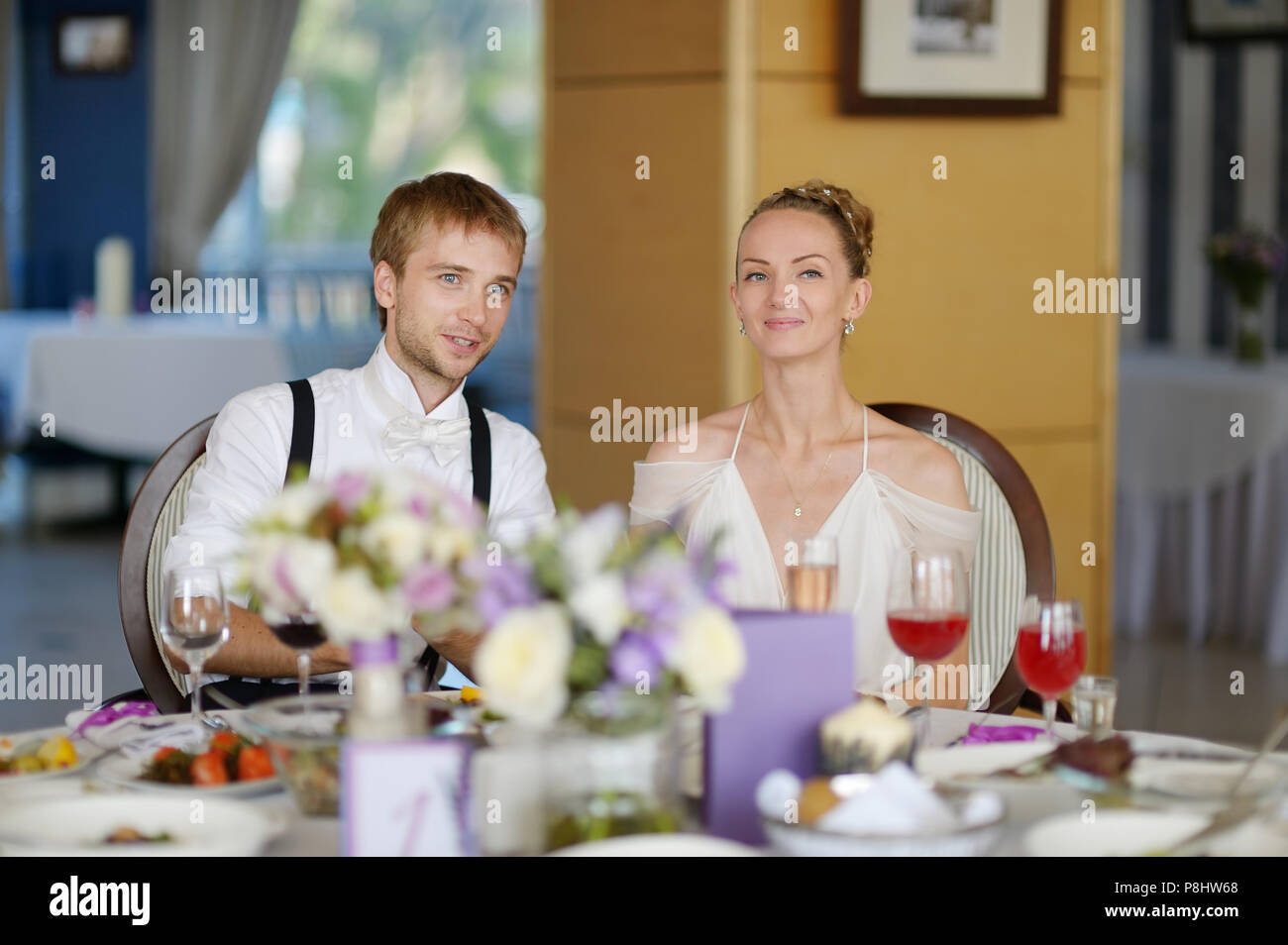 Happy bride and groom at the reception table Stock Photo - Alamy