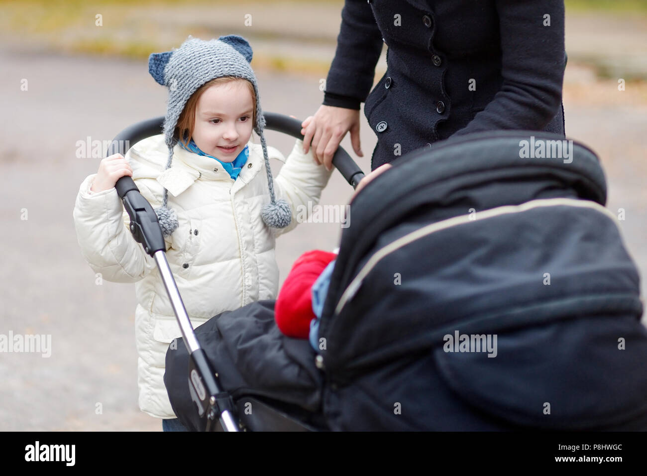 Little sister pushing a stroller with her little sibling Stock Photo ...