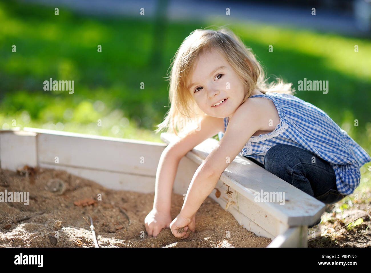 Adorable little girl playing in a sandbox Stock Photo - Alamy