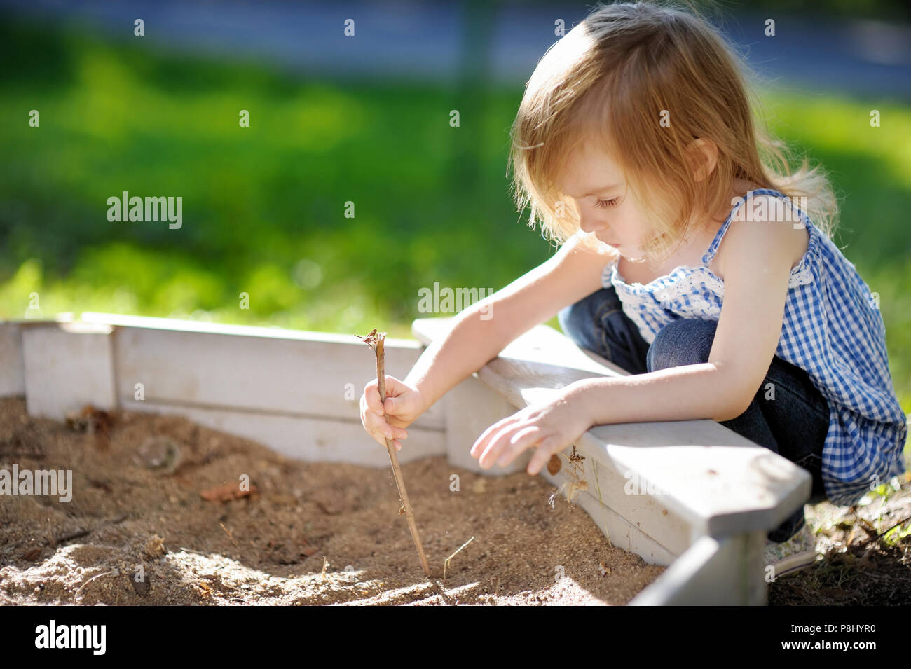 Adorable little girl playing in a sandbox Stock Photo - Alamy