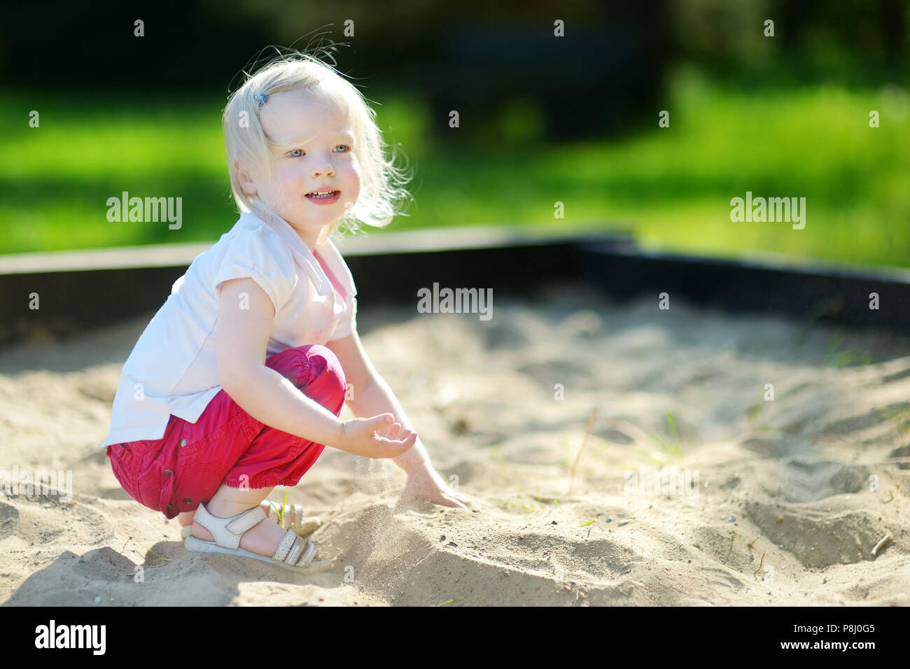 Adorable little girl playing in a sandbox Stock Photo - Alamy