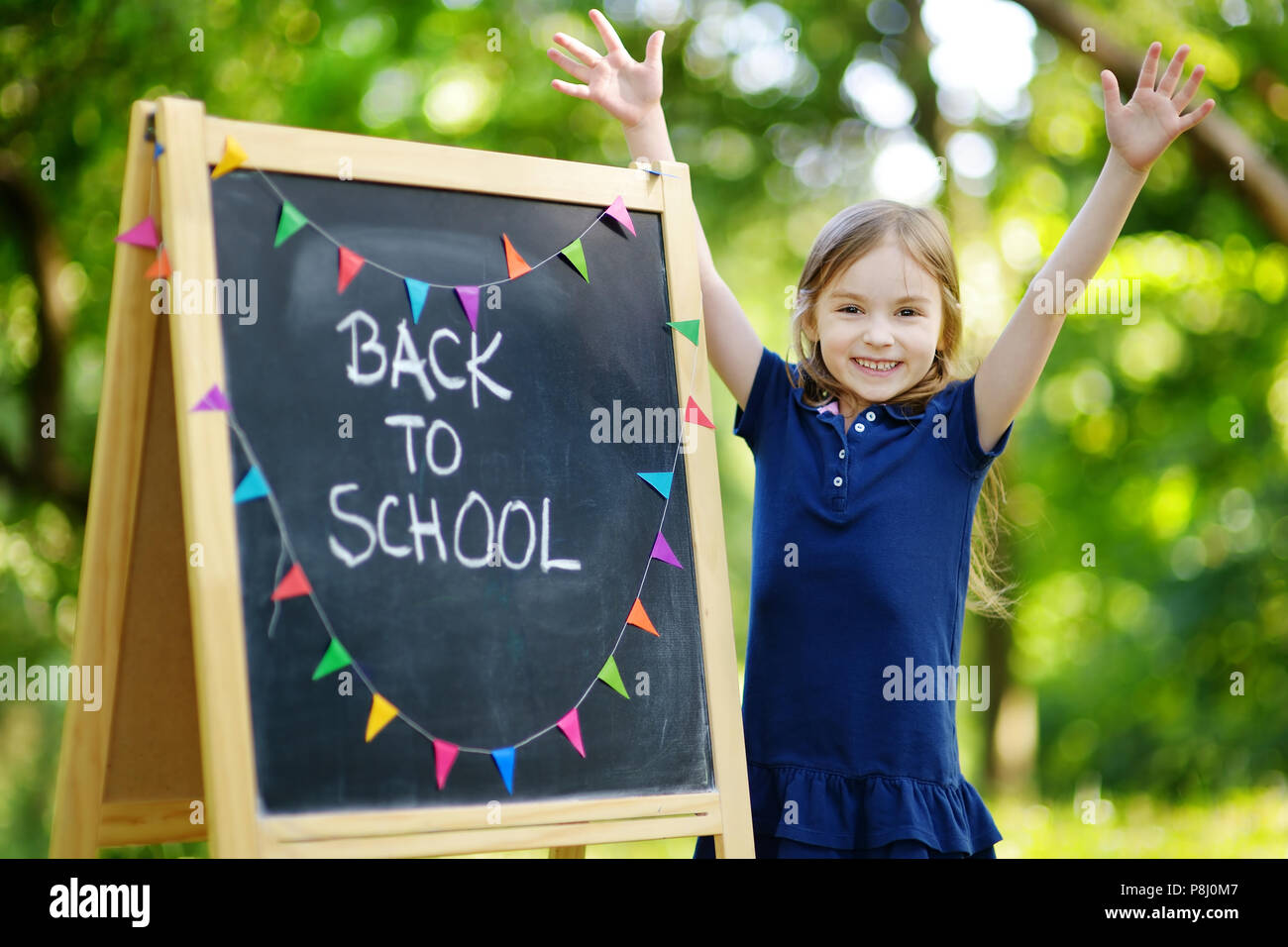 Adorable little schoolgirl feeling very excited about going back to ...