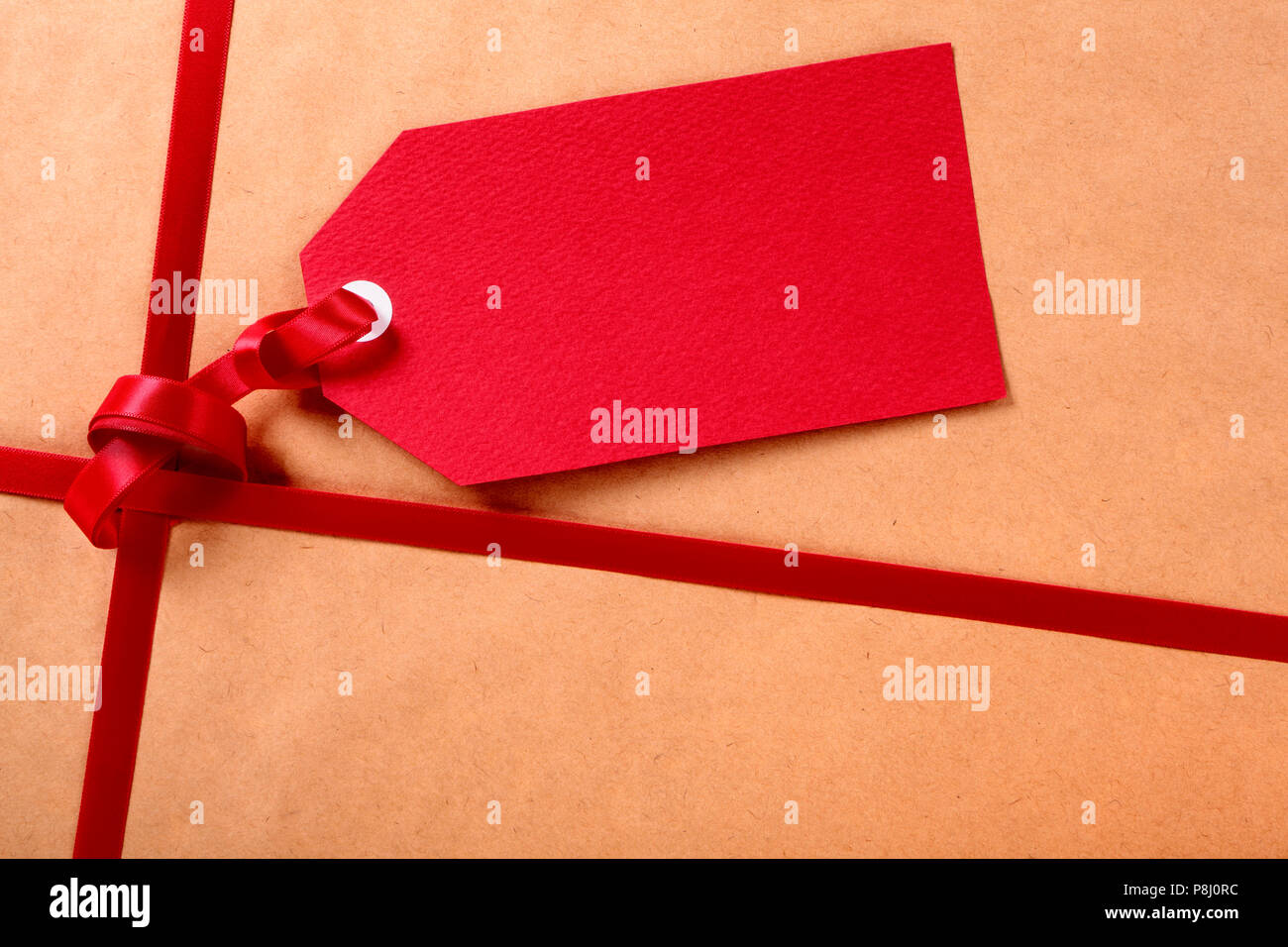 Red gift tag and ribbon, brown parcel wrapping paper background, copy ...