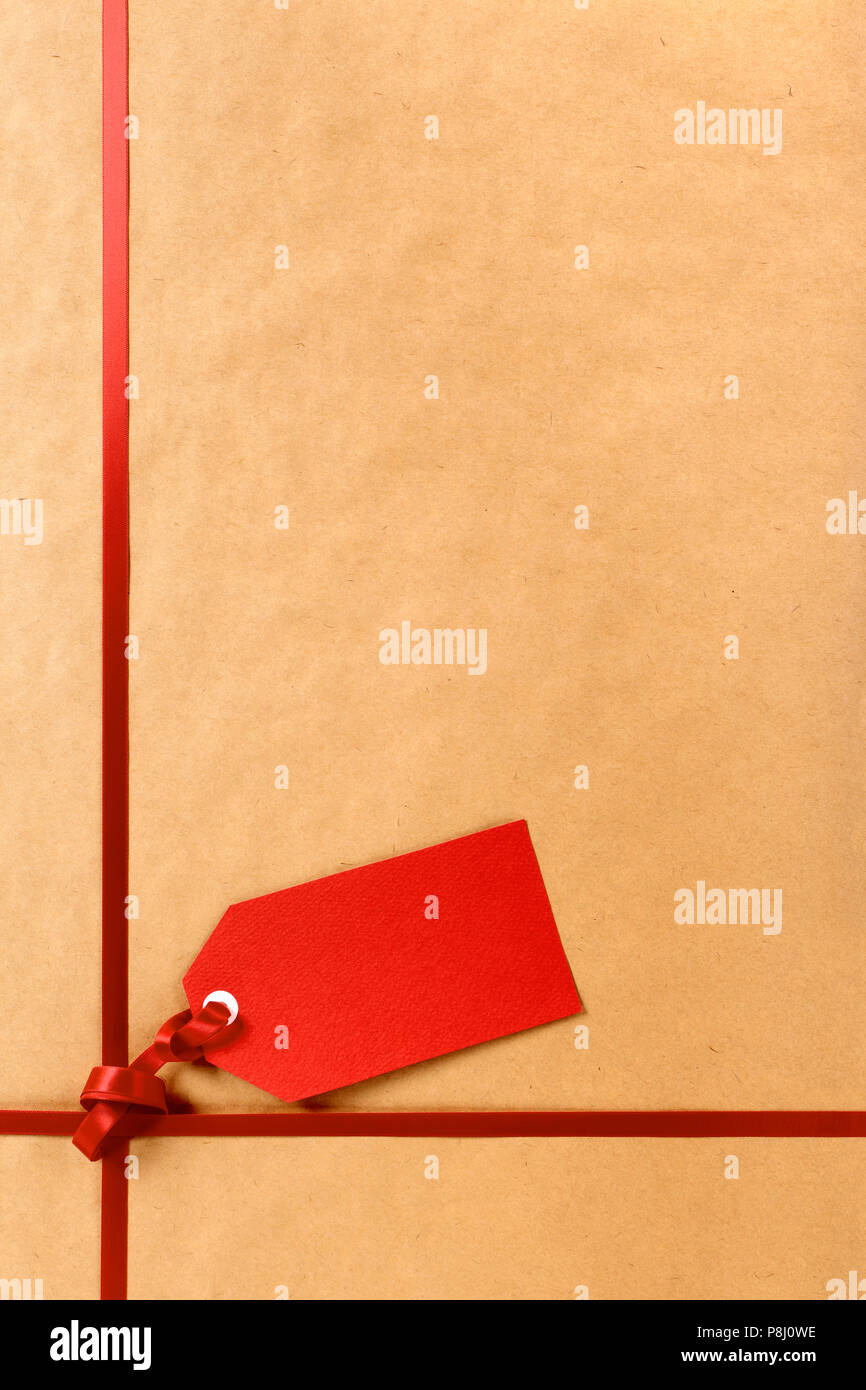 Red gift tag and ribbon, brown parcel wrapping paper background, copy ...