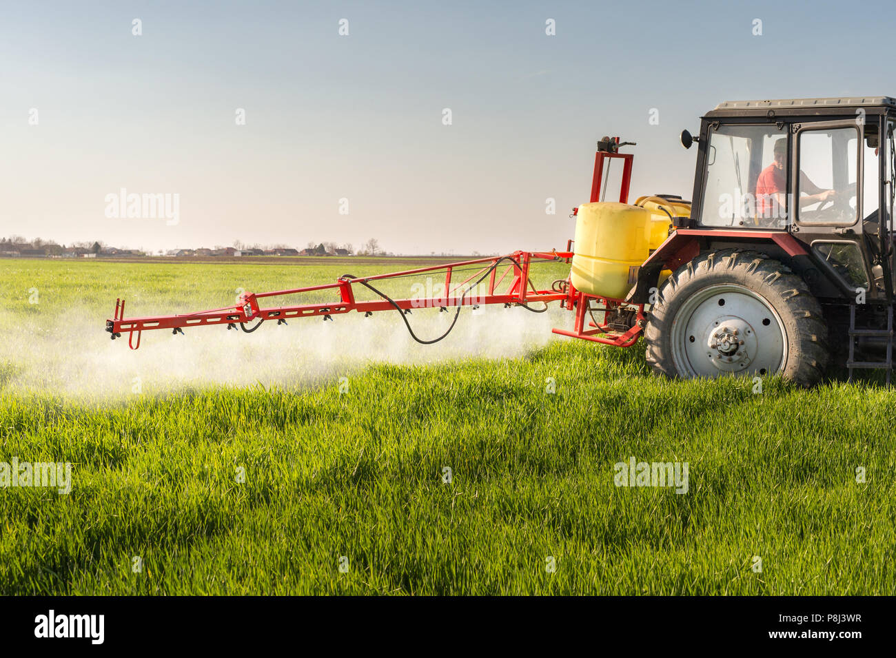 Tractor spraying wheat field with sprayer Stock Photo - Alamy