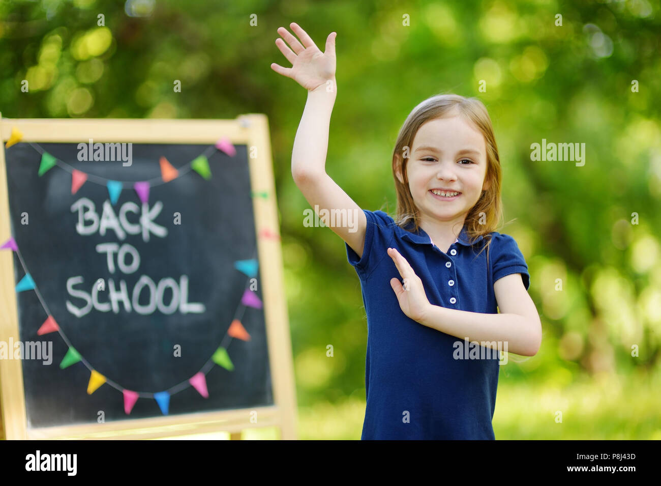 Adorable little schoolgirl feeling extremely excited about going back ...
