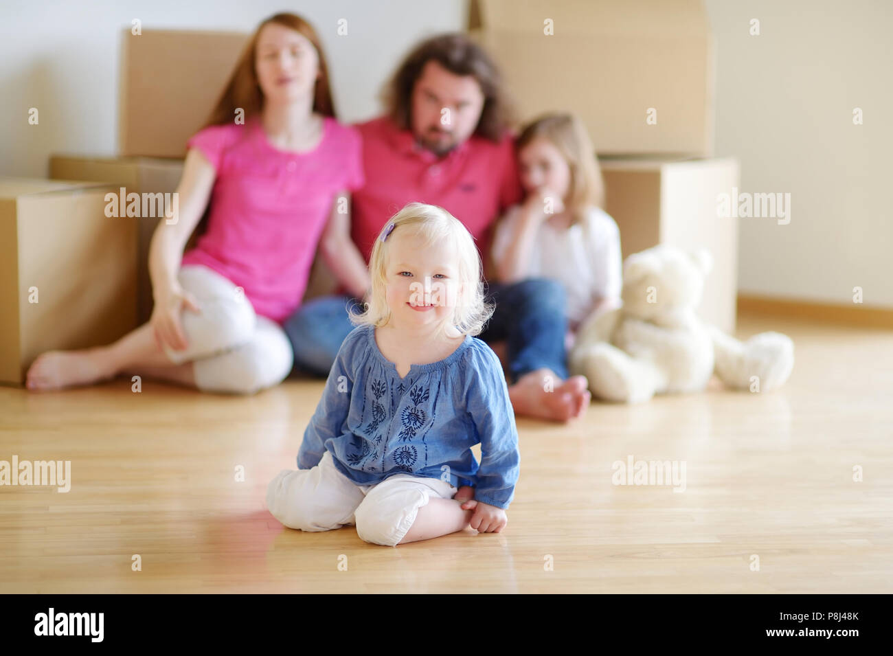 Happy little toddler girl moving in her new home with parents and a ...
