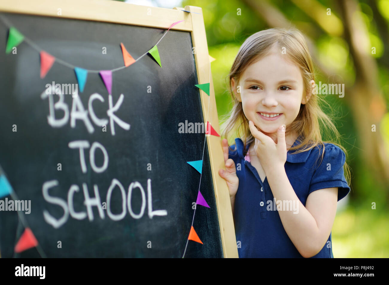 Adorable little schoolgirl feeling extremely excited about going back ...