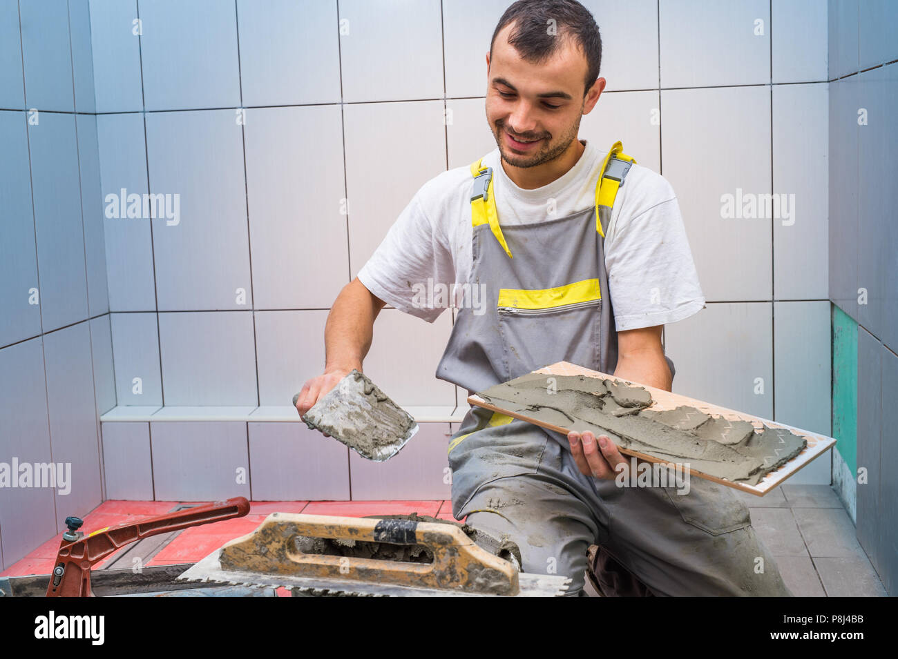 industrial tiler builder worker installing floor tile Stock Photo - Alamy