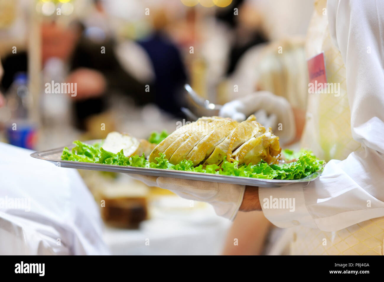 Waiter carrying a plate with delicious meat dish at party or reception ...