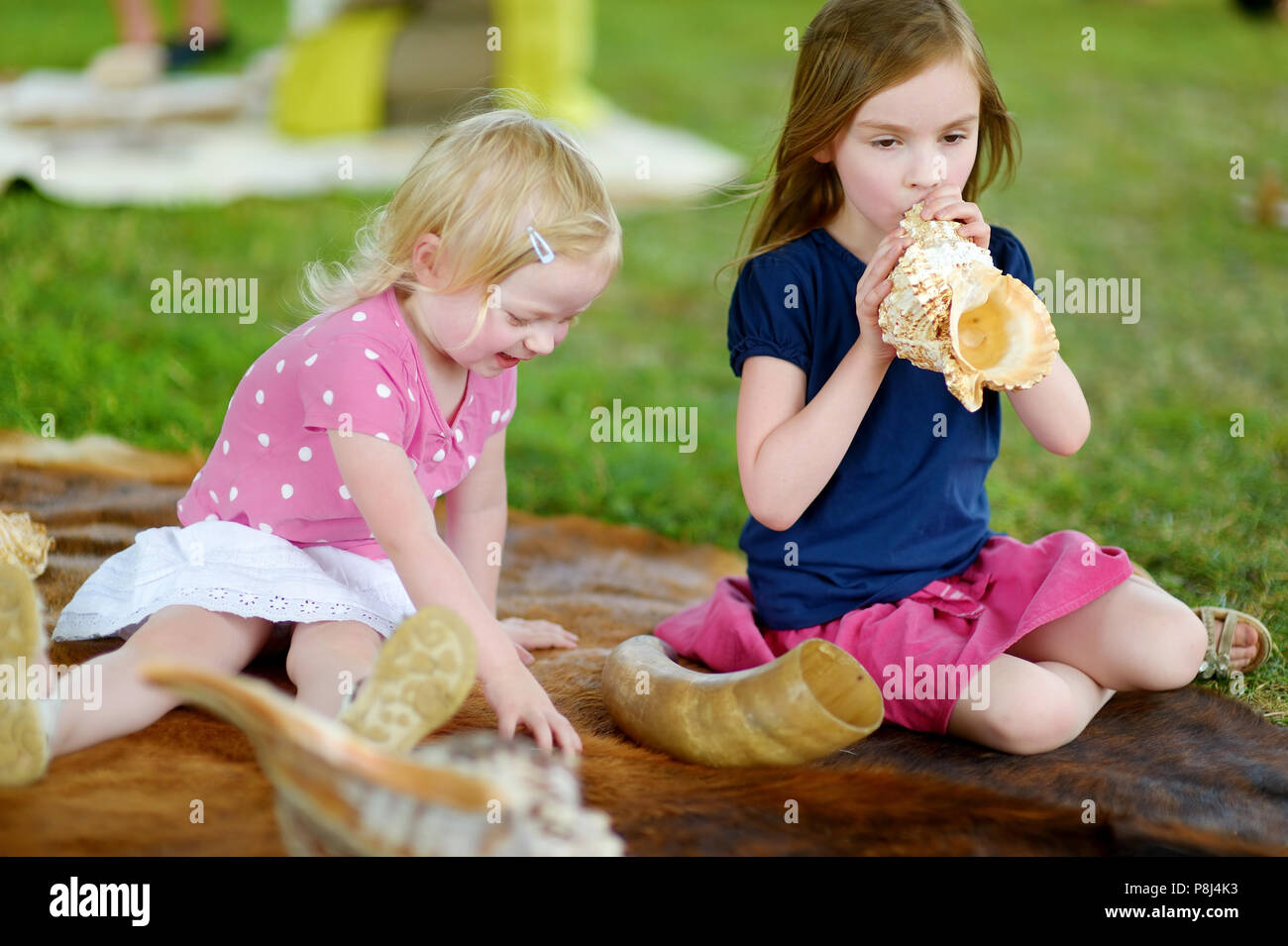 Two little sisters playing with shells on summer day Stock Photo - Alamy