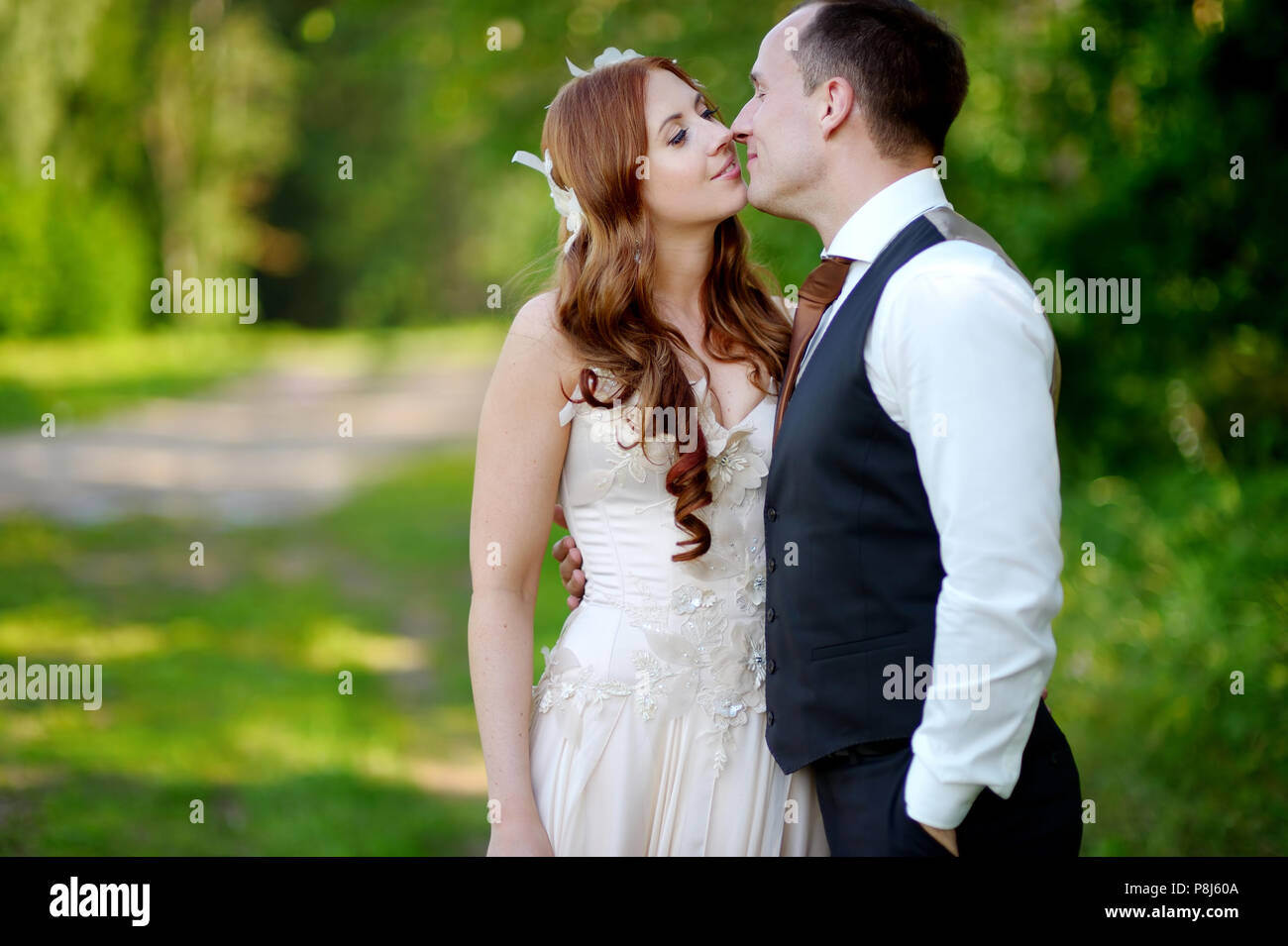 Young bride and groom hugging and kissing in beautiful summer park ...