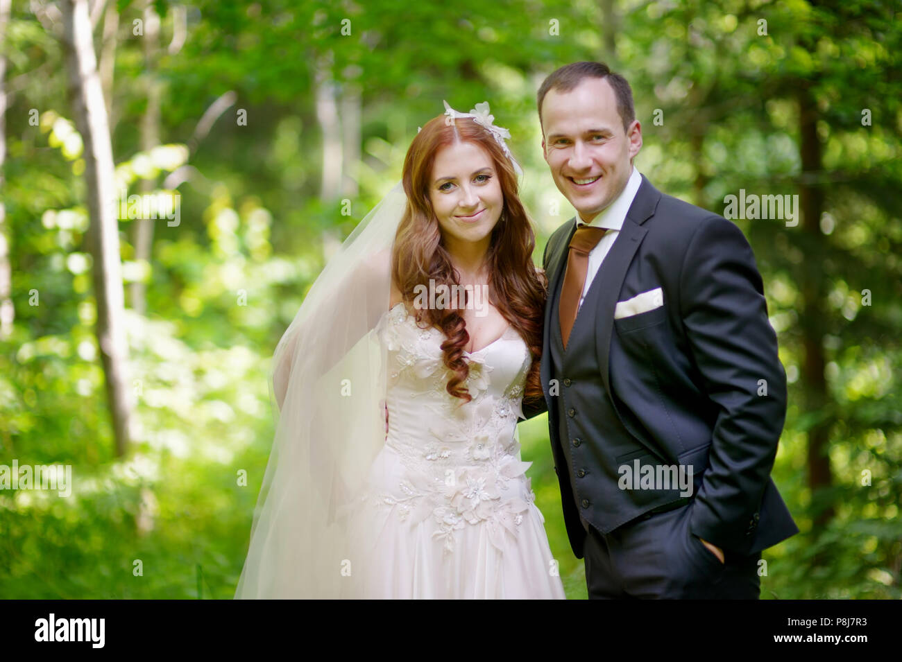 Young bride and groom hugging and kissing in beautiful summer park ...