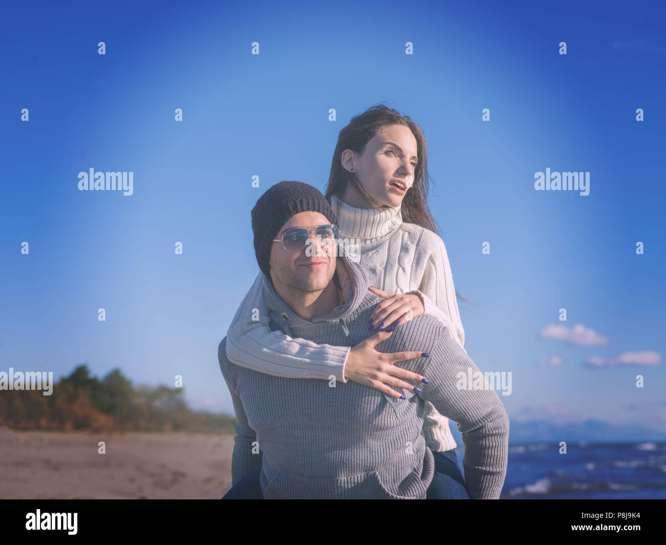 Men Giving Piggy Back Rides At Sunset By The Sea, autumn time colored ...