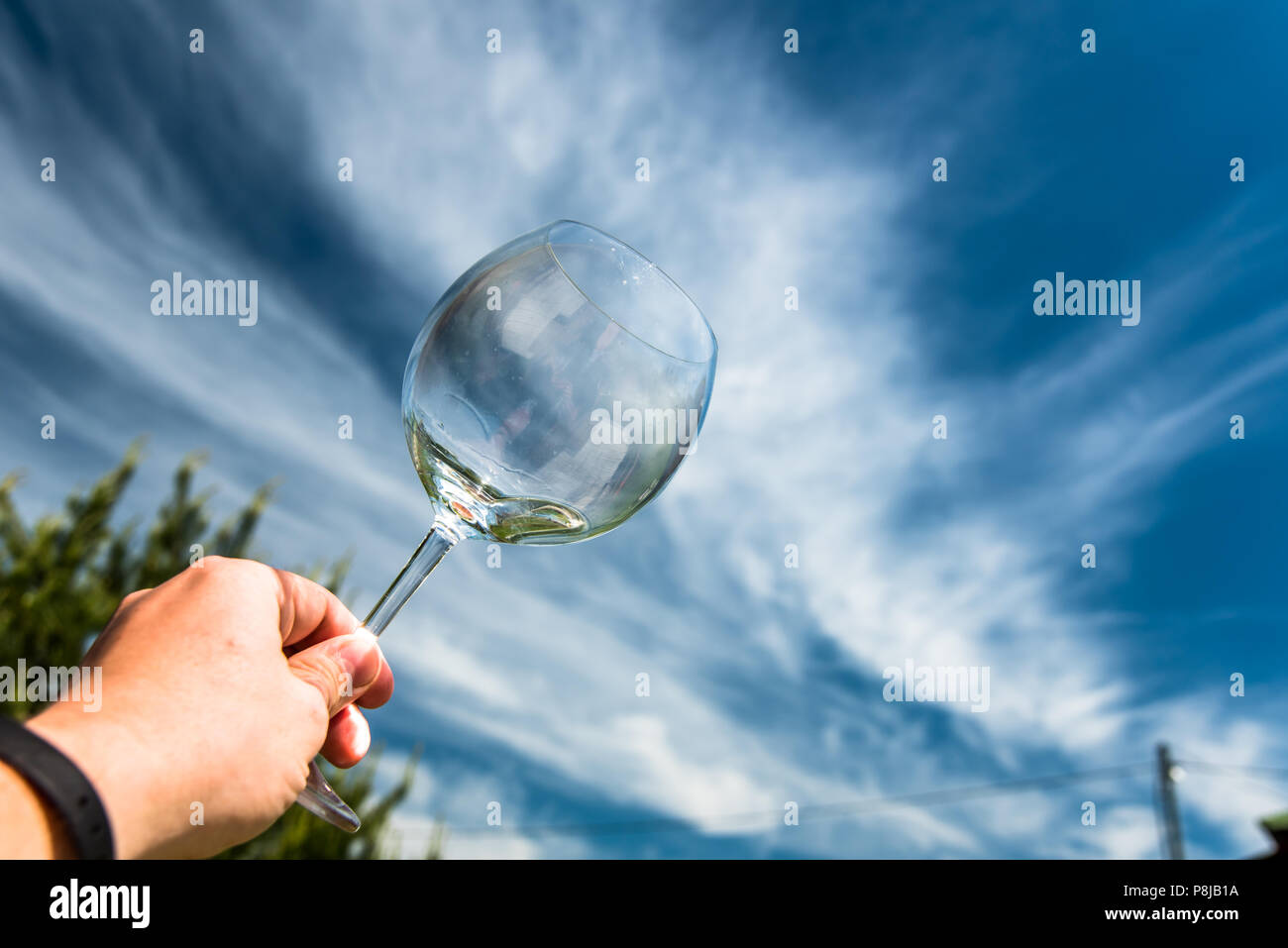Empty clear glass in hand on blue sky background Stock Photo - Alamy