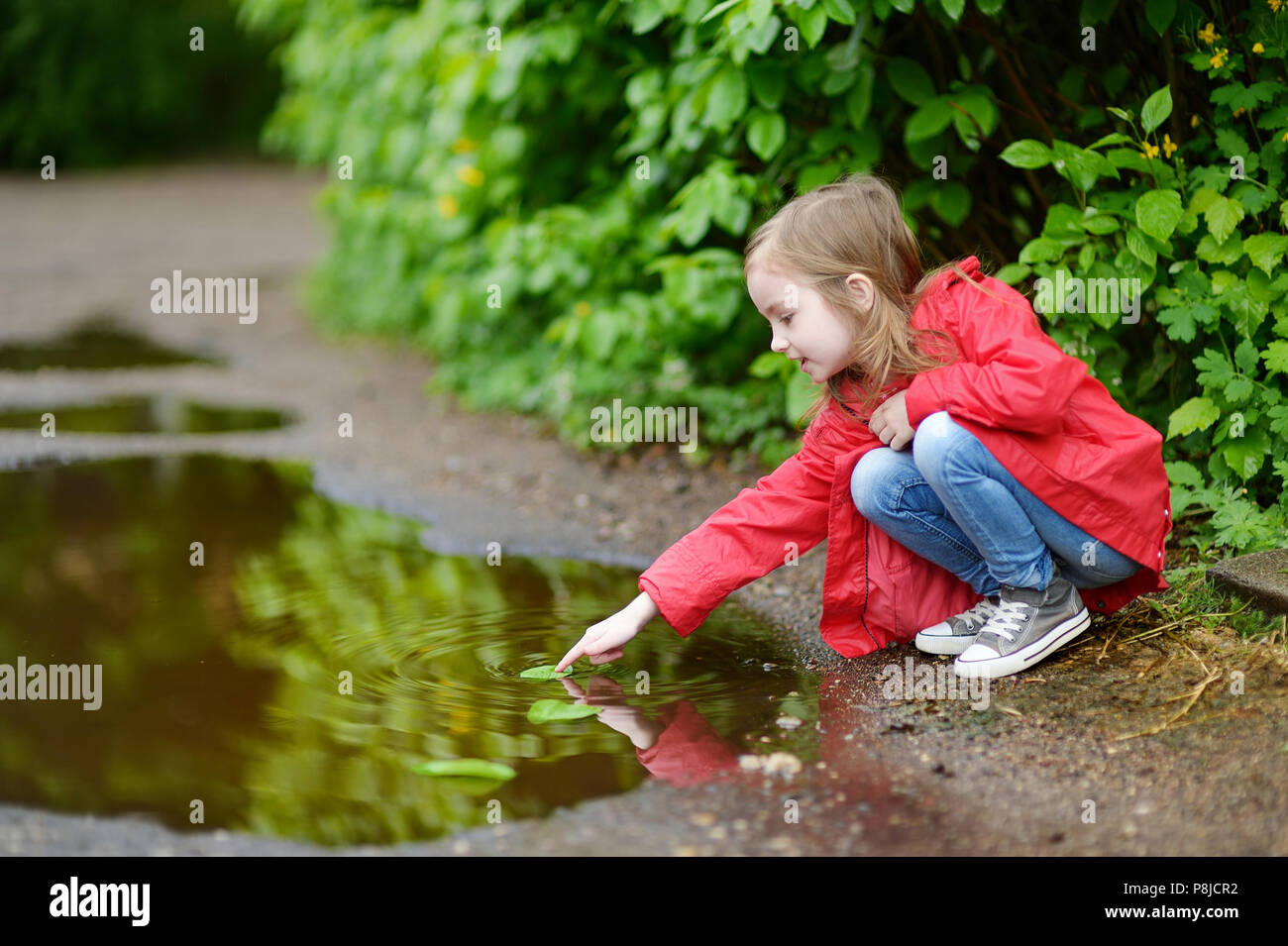 Adorable girl playing in a puddle on rainy summer day Stock Photo - Alamy