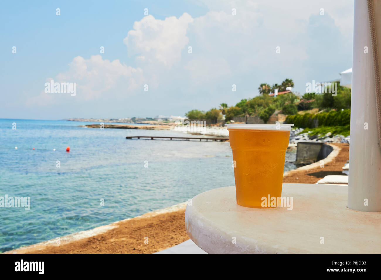 A glass of beer on the beach with beautiful sea view of background ...