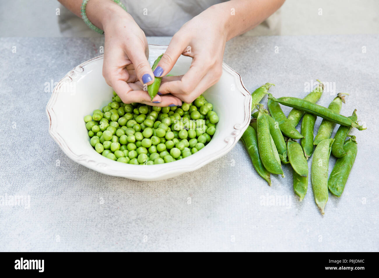 Woman hands hulled peas from shell on grey bright surface Stock Photo ...