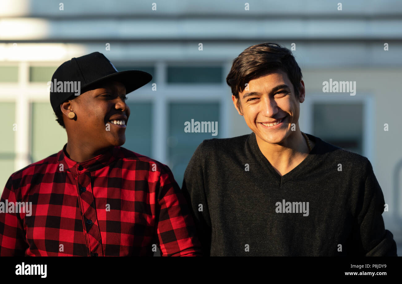 black friend and white friend outdoors in an informal portrait chatting ...