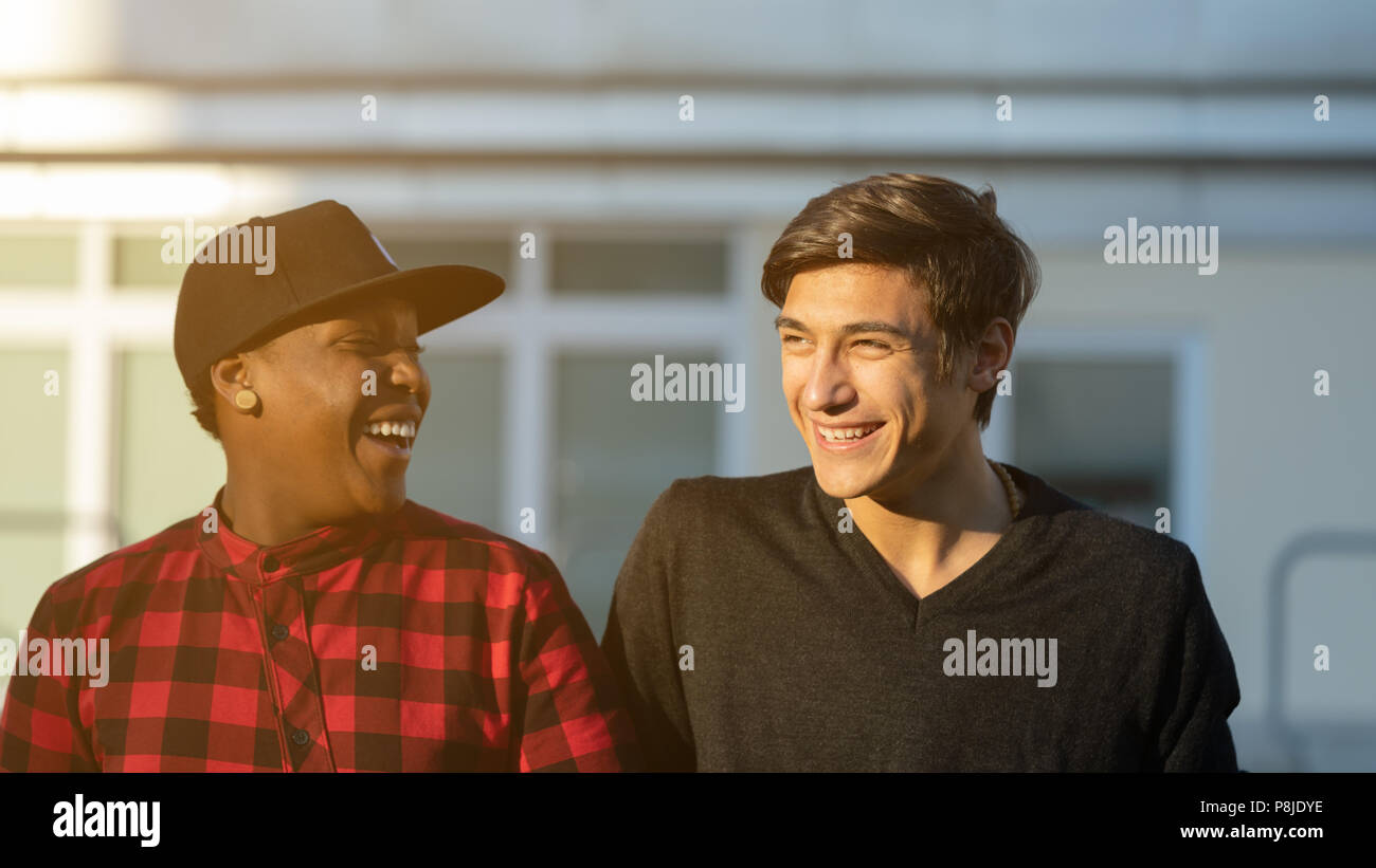 black friend and white friend outdoors in an informal portrait chatting ...